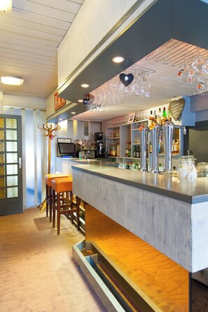 Uma área de bar com balcão, banquetes e diversas garrafas e copos.