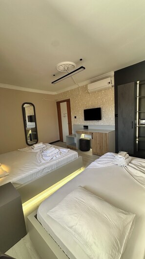 Quarto de hotel com duas camas, uma televisão de tela plana, um espelho e uma escrivaninha com cadeira.