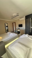 Quarto de hotel com duas camas, uma televisão de tela plana, um espelho e uma escrivaninha com cadeira.