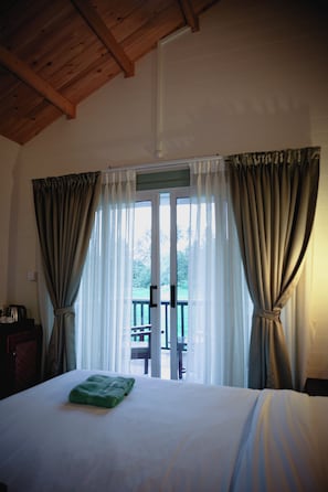 Um quarto com uma cama, cortinas e vista para um terraço ao ar livre.