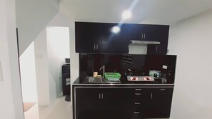 Uma cozinha compacta com bancada preta, pia e fogão.
