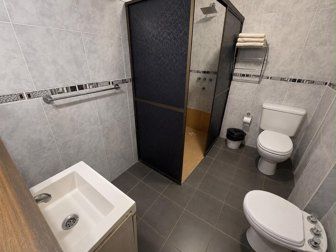 A bathroom with a white sink, a toilet, and a shower area.