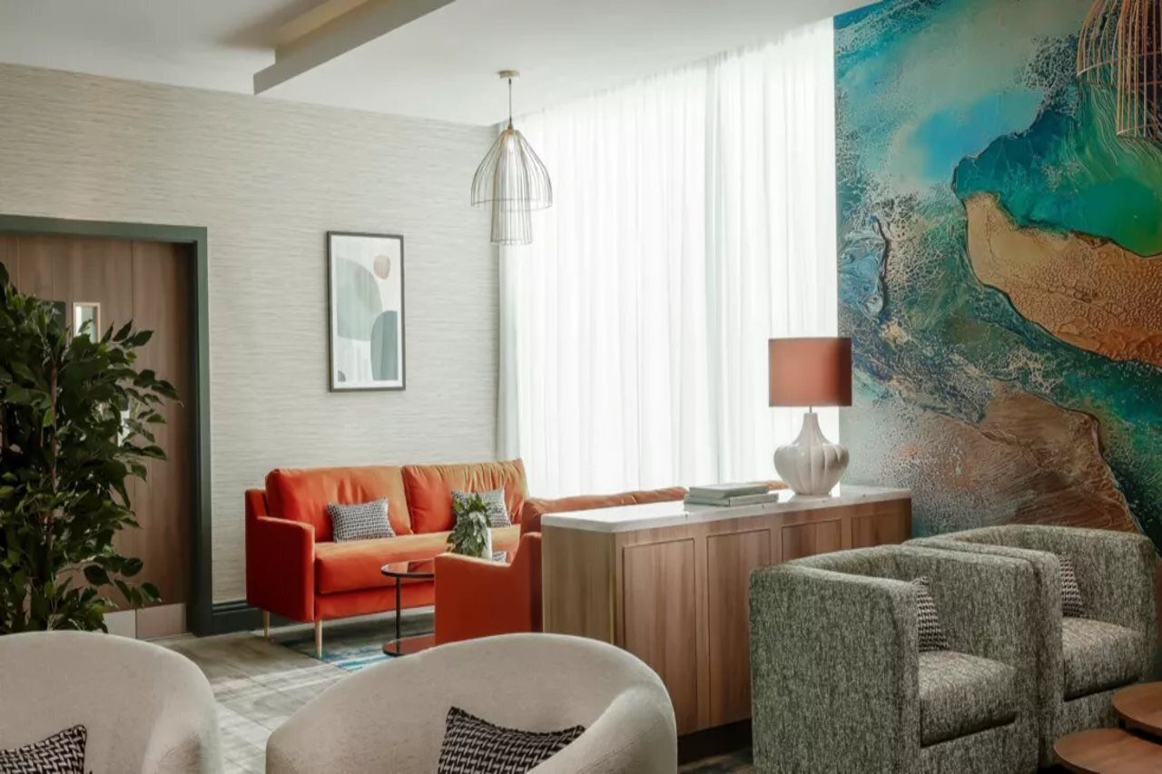 Uma sala de estar moderna com um sofá vermelho, uma poltrona cinza e uma mesa de centro de madeira.