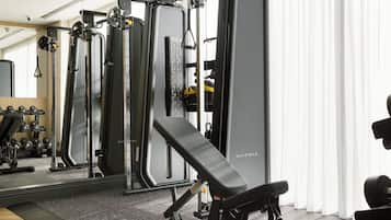 Uma academia com diversos equipamentos de exercício, incluindo aparelhos de musculação e halteres.