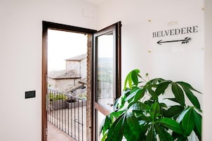 Uma entrada que dá para uma varanda com vista para edifícios e uma placa indicando 'BELVEDERE'.