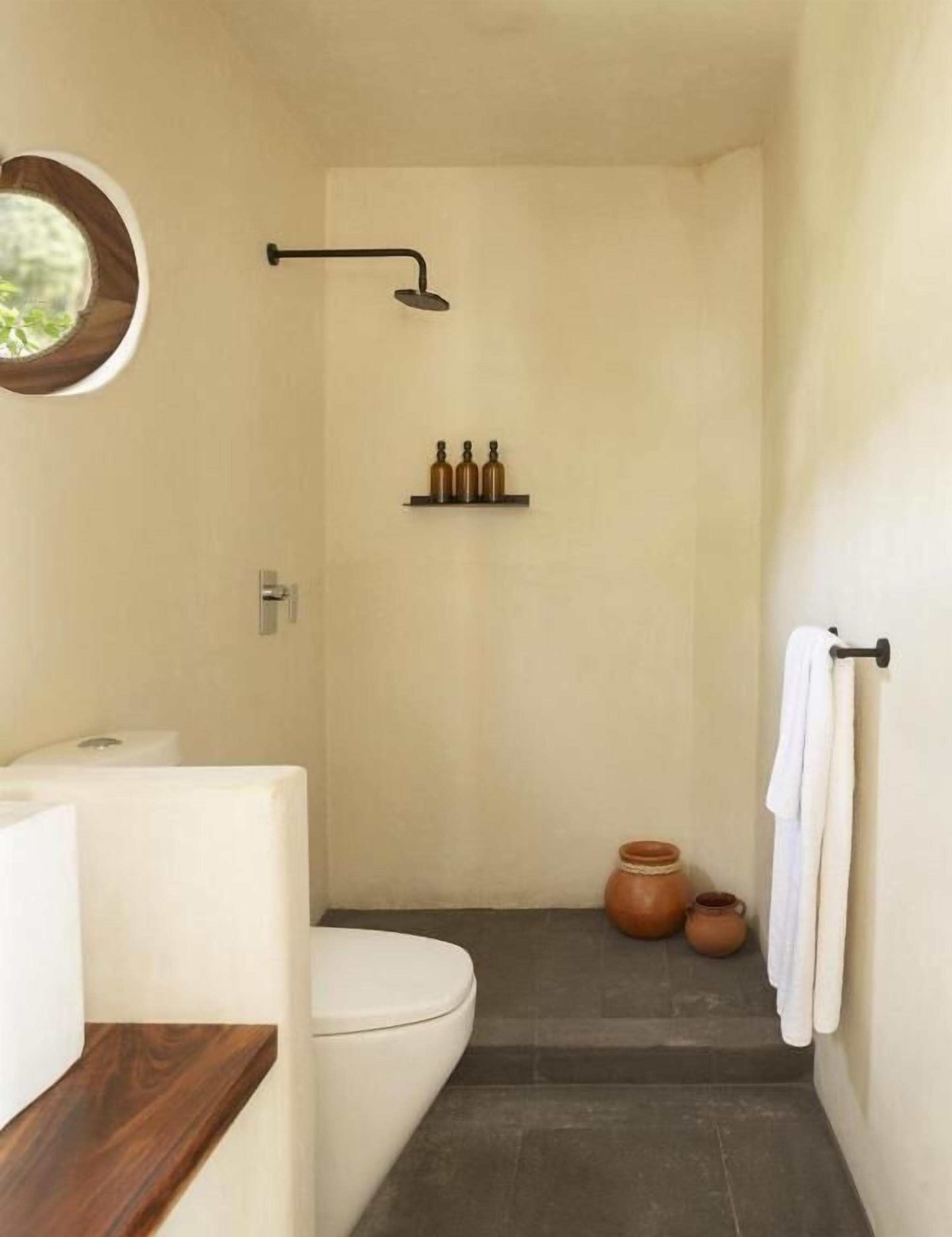 Casa de banho pequena com sanita, chuveiro e um pequeno armário com frascos.