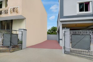 Portão fechado para um prédio residencial com fachada curva e caminho vermelho que leva à entrada.