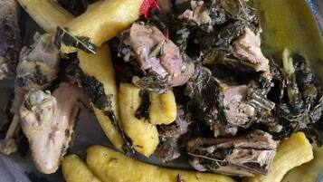 Prato com frango, folhas verdes e legumes amarelos em uma tigela de metal.