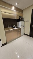 Uma cozinha com micro-ondas, geladeira e painel de azulejos.