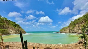Paisagem costeira com céu claro, mar calmo e falésias rochosas.