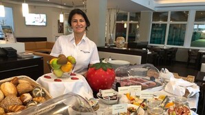 Buffet com diversos alimentos e uma pessoa atrás.