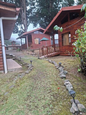 Uma fileira de cabanas de madeira com um caminho de pedra que leva a um gazebo.