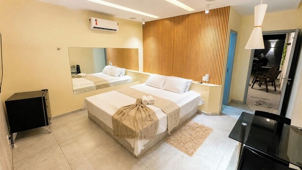 Quarto de hotel com duas camas, um espelho, uma escrivaninha e uma cadeira.