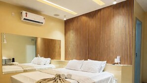 Quarto de hotel moderno com uma cama grande, uma mesinha de cabeceira, um espelho e painel de parede de madeira.