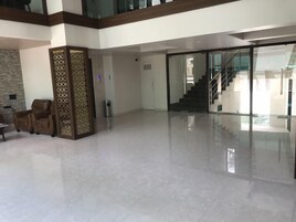 Um hall amplo com teto alto, escadaria e área de estar com cadeiras.