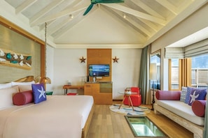Quarto de hotel com cama, sofá, escrivaninha com televisão e varanda com vista.