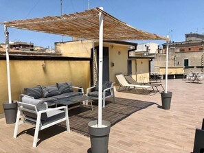 Um pátio externo com um sofá, cadeiras e um toldo.