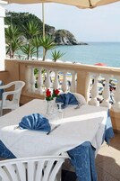 Mesa posta para dois com vista para o mar e costa rochosa.