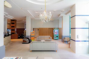 Um lobby moderno com um lustre, um balcão de recepção, um sofá e uma máquina de pegada.