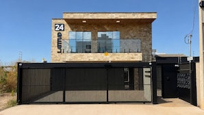 Um edifício moderno com fachada de pedra, número 24, e um portão de metal preto.