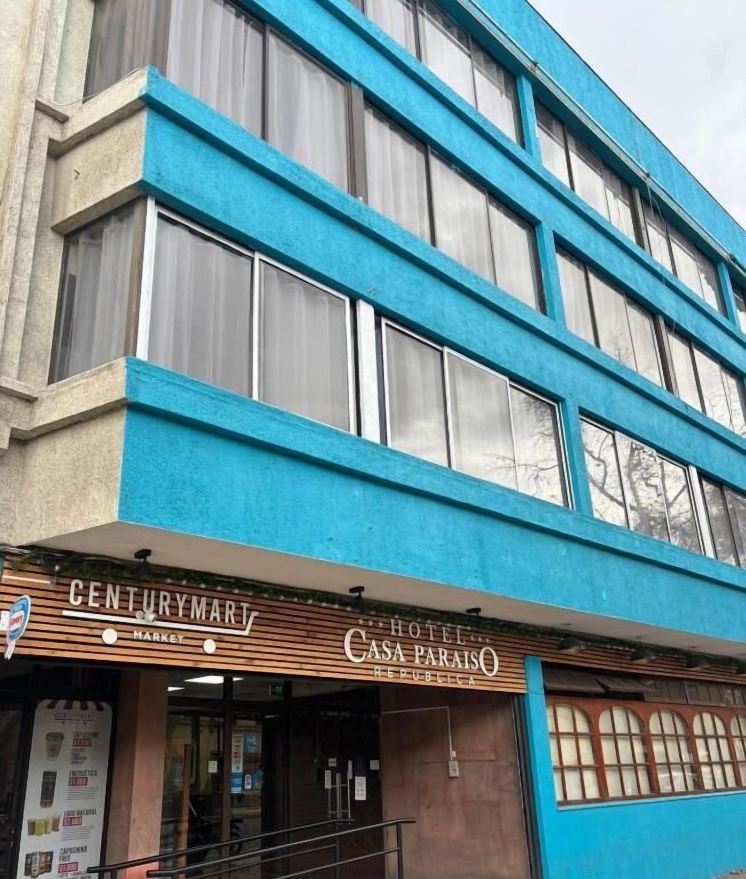 Um edifício com fachada azul, fachada de madeira e uma placa com a inscrição 'CENTURYMARK HOTEL CASA PIRATA R.E.PUBECIA'.