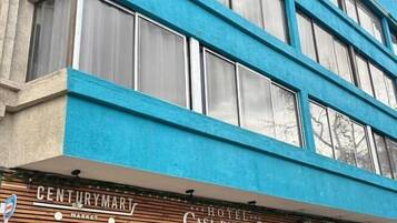 Um edifício com fachada azul, fachada de madeira e uma placa com a inscrição 'CENTURYMARK HOTEL CASA PIRATA R.E.PUBECIA'.