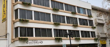 Um hotel de vários andares com fachada plana, grandes janelas e plantas externas.