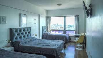 Quarto de hotel com duas camas, uma escrivaninha e vista para a cidade.