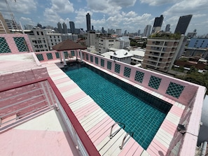 Piscina no terraço com vista para a cidade, cercada por edifícios.