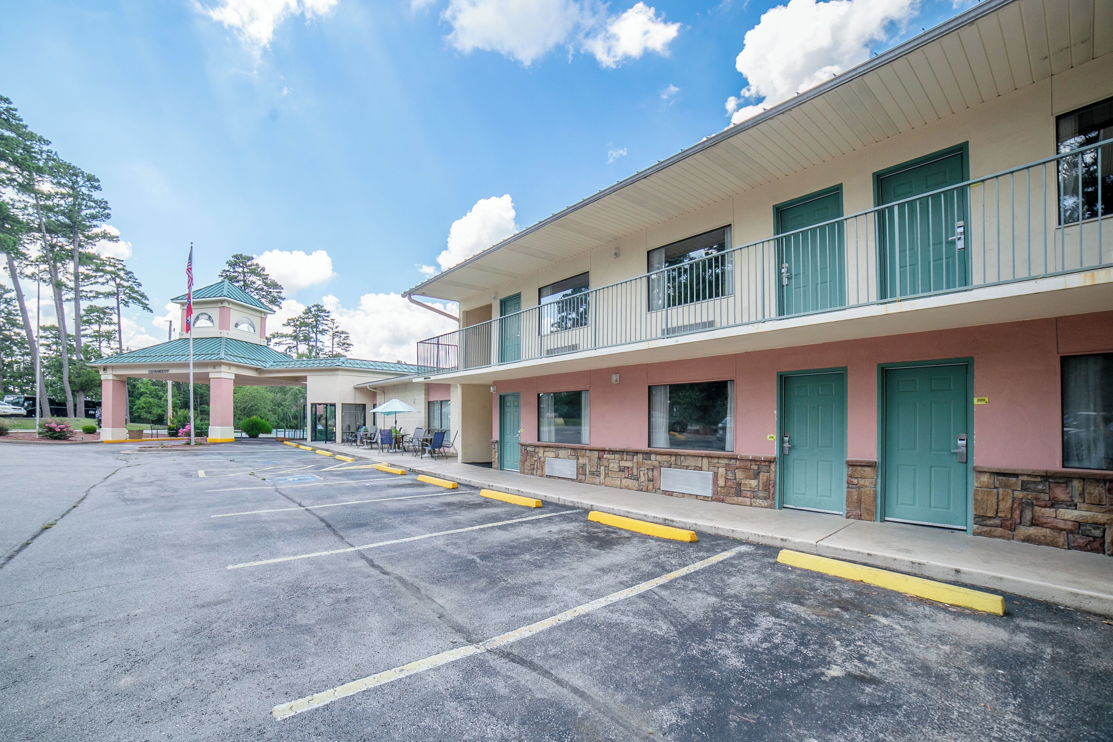 Um motel de dois andares com um estacionamento à frente.