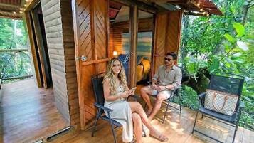 Uma cabana de madeira com varanda, duas cadeiras e uma bolsa em um banco.