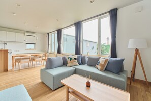 Uma sala de estar moderna com um sofá, uma área de jantar e uma cozinha.