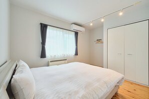 Quarto com cama, janela com cortinas, ar-condicionado, guarda-roupa e cabideiro.