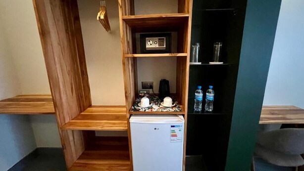 A compact kitchenette with a refrigerator, a microwave, and a small coffee maker. There are two water bottles on the counter.