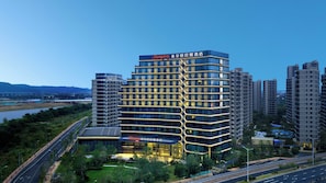 Um hotel de vários andares com design moderno, destacando uma placa grande no topo.