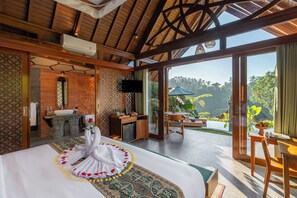 Quarto de hotel com uma cama grande, uma escrivaninha, uma televisão e vista para o exterior.