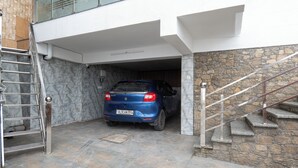 Um carro estacionado em uma garagem com parede de pedra e escada de metal.