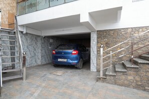 Um carro estacionado em uma garagem com parede de pedra e escada de metal.
