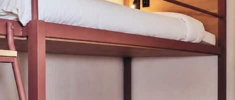 Uma cama beliche com escada, cabeceira de madeira e roupa de cama branca.