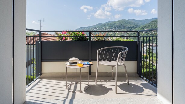 A balcony with two chairs, a small table, and a potted plant.