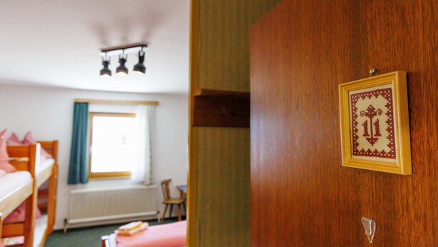 Quarto com beliches, um quadro pendurado na parede e uma janela com cortinas.