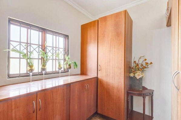 Uma cozinha com armários de madeira, uma janela com plantas e uma pequena mesa com flores.