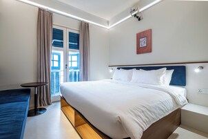 Quarto de hotel com uma cama grande, uma mesinha e vista para o exterior.