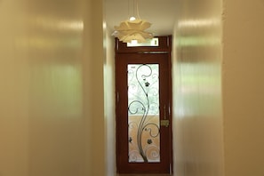 Um corredor com uma porta de madeira, com um painel de vidro decorativo com motivos florais.