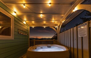Área de hidromassagem com vista para o pôr do sol, um deck de madeira e um aviso de segurança.