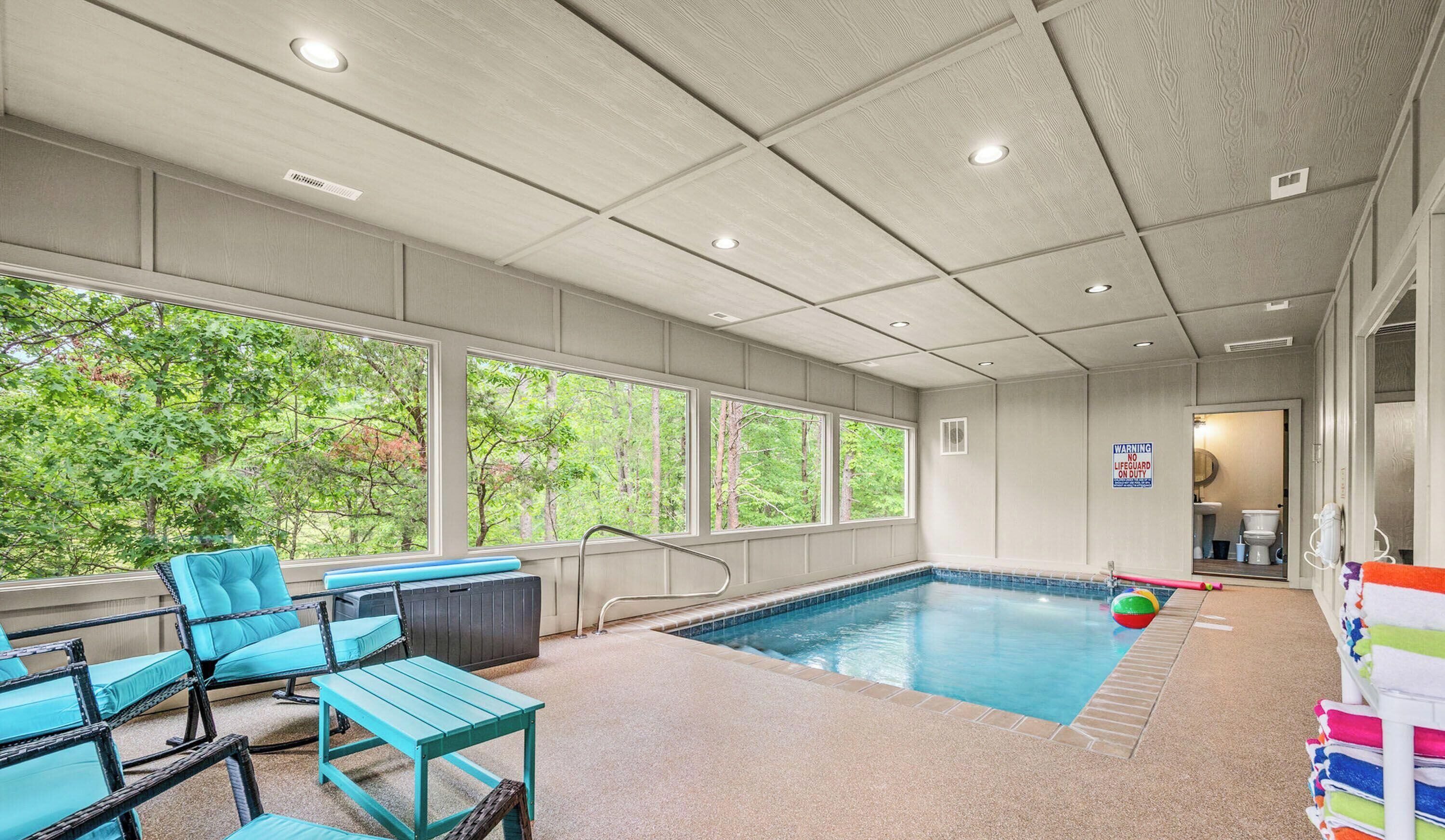 Piscina coberta interna com assentos e vista para árvores.
