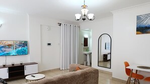 Uma sala de estar moderna com sofá, televisão e área de refeições.