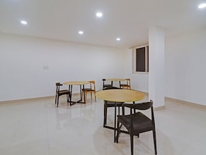 Um quarto com soalho em azulejos, uma janela e uma mesa com cadeiras.