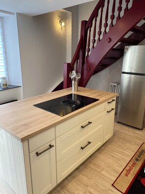 Cozinha com bancada de madeira, eletrodomésticos de aço inoxidável e escada vermelha.