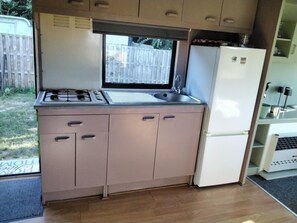 Uma cozinha compacta com fogão a gás, pia e geladeira.